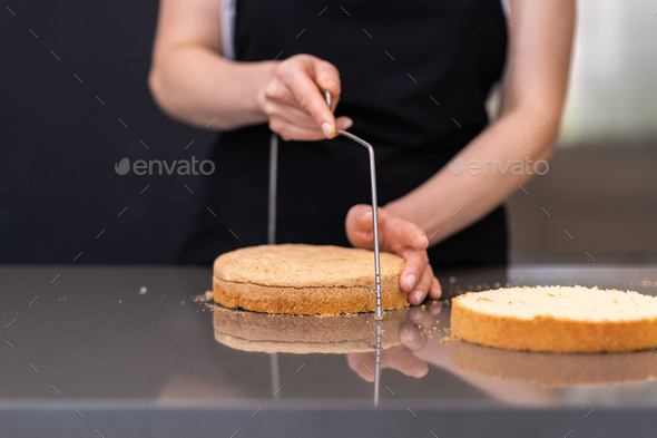 Skilled woman using string knife for separating cake layers in modern ...