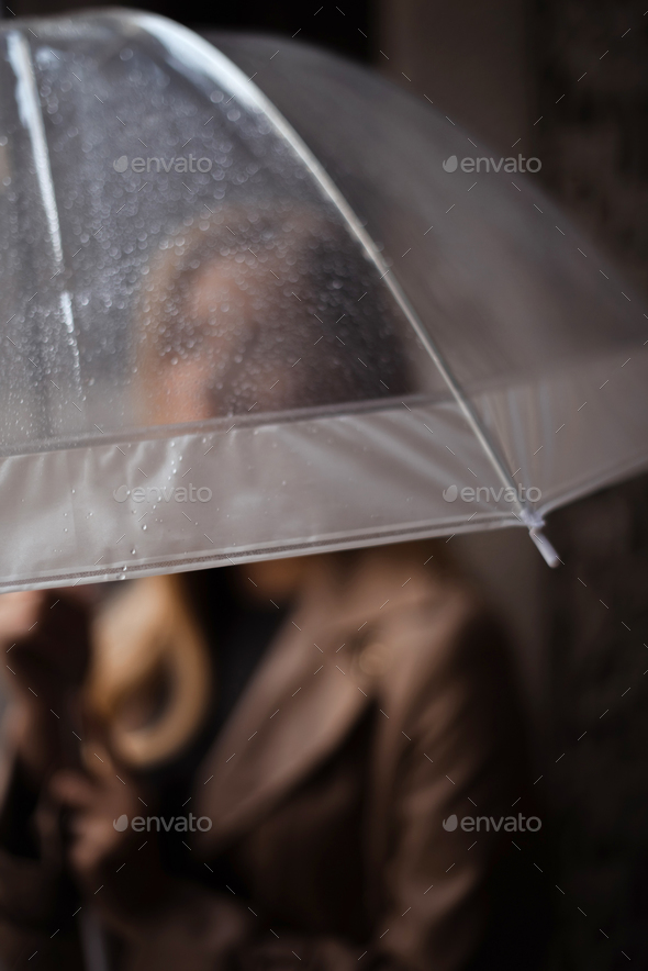 focus on rain drops on transparent umbrella in woman hand in rainy day ...