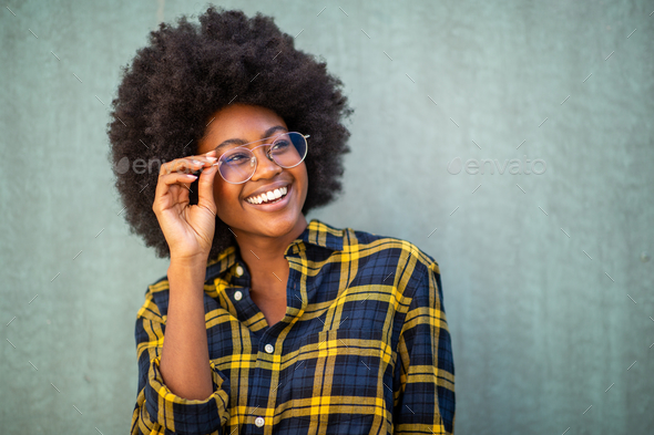 Pretty young afro woman with eyeglasses standing by green wall Stock ...