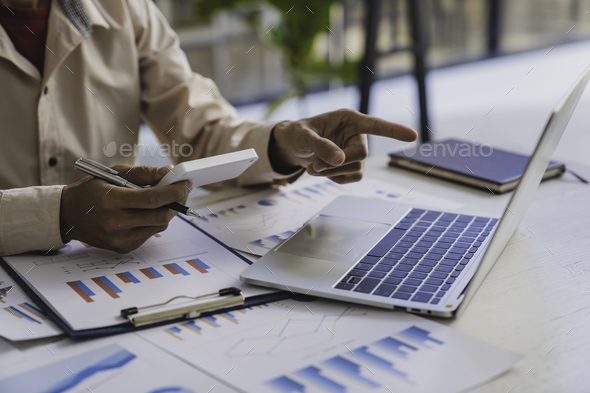 Businessmen hold graph pens and use a calculator for the company's ...