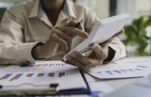Businessmen hold graph pens and use a calculator for the company's ...