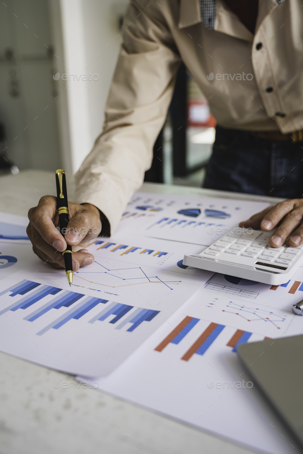 Businessmen hold graph pens and use a calculator for the company's ...