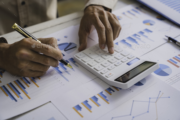 Businessmen hold graph pens and use a calculator for the company's ...