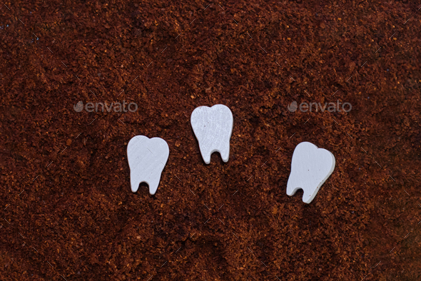 Large white tooth on a pile of roasted coffee beans. Coffee staining ...