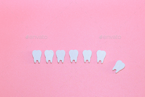 Wooden teeth with a lost molar on a pink background. Dental concept ...