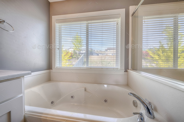 Closeup shot of a jacuzzi bathtub in a bathroom with big window and ...