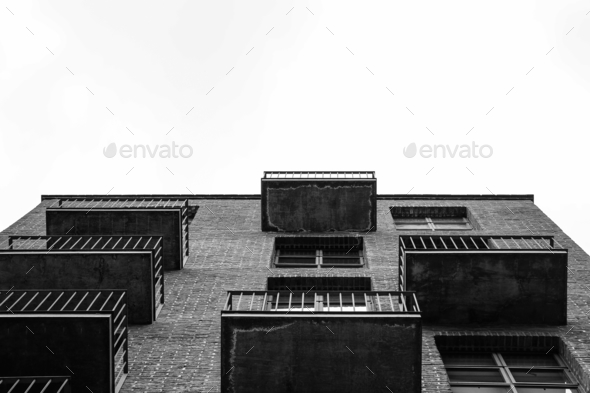 Grayscale shot of a brick building facade on a white sky background ...