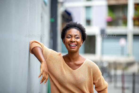 smiling young black woman leaning against wall outside Stock Photo by ...