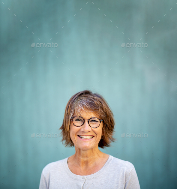 Close up woman in 50s smiling by green background Stock Photo by ...