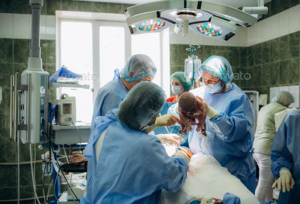 Doctor and nurse are pulling a new born baby from mom's abdomen Stock ...