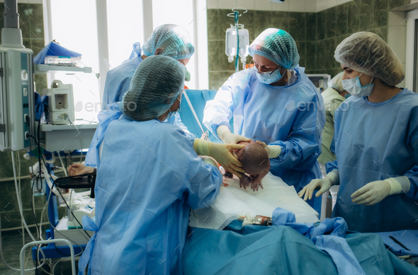 Doctor and nurse are pulling a new born baby from mom's abdomen Stock ...