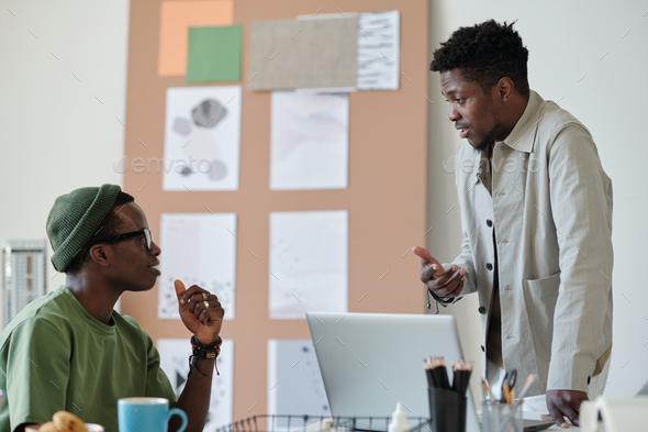 Side view of two young African American designers discussing working ...