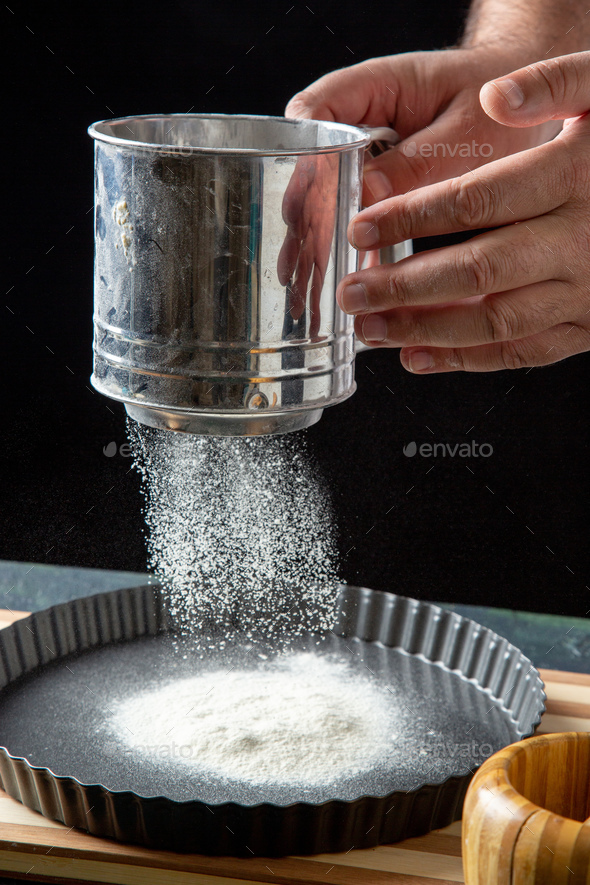 Half body shot of male chef sifting flour in the kitchen in vertical ...