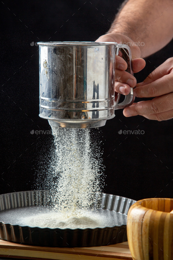 Half body shot of male chef sifting flour in the kitchen in side view ...