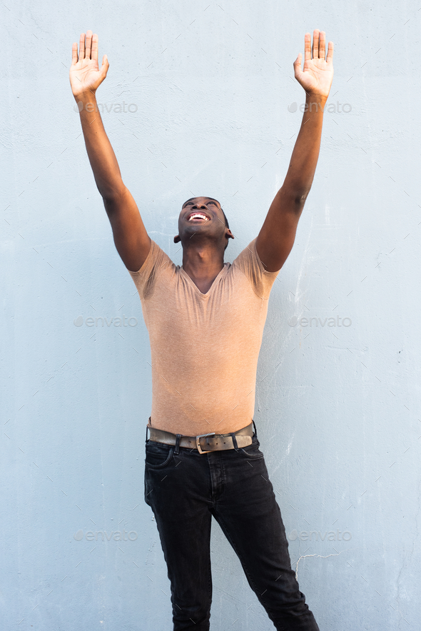 cheerful young black man with hands raised and looking up Stock Photo ...