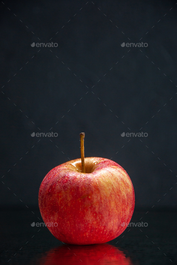 Vertical view of red fresh apple standing on dark wave background with ...