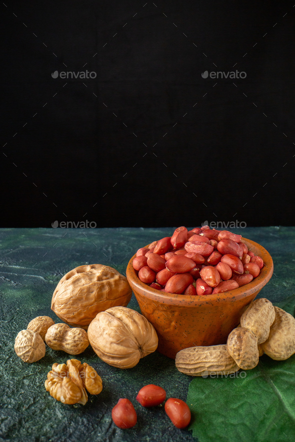 Close up view of red peanuts inside and outside of a small brown pot ...