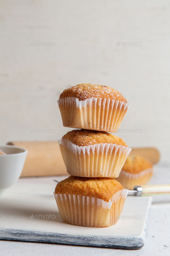 a front view little cakes inside paper forms with sugar powder on the ...