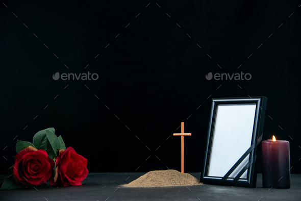 front view of little grave with candle and picture frame on dark ...