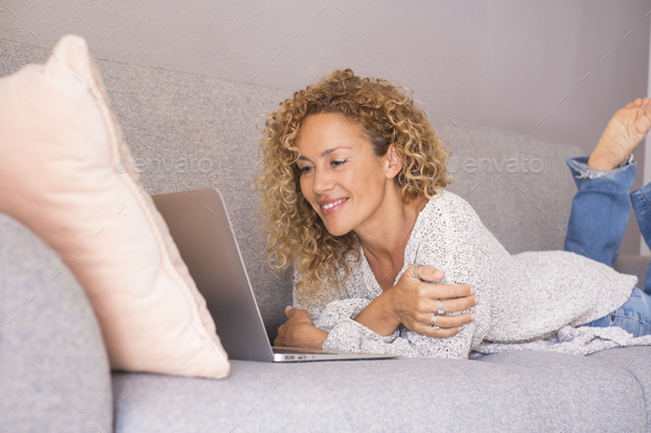 Portrait of happy young adult womn using computer laying down on the ...