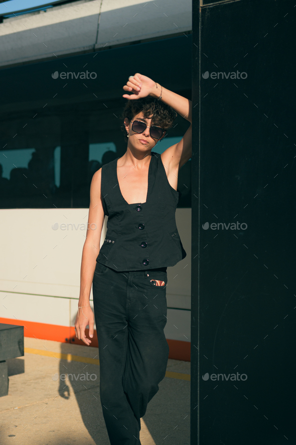 Young alternative man in black clothes posing in a station at sunset ...