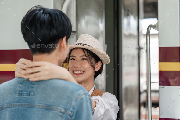 positive girlfriend hugging pleased man while locating near train Stock Photo by nateemee