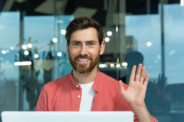 Portrait of a young male programmer in a red shirt working in the ...