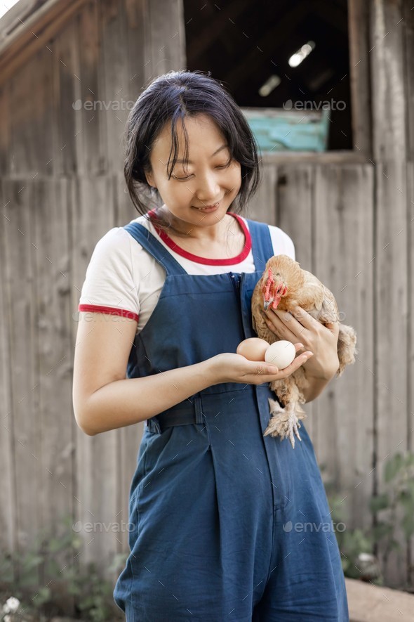 The farmer hugs a hen. pleasant asian woman is hugging a cock in ...