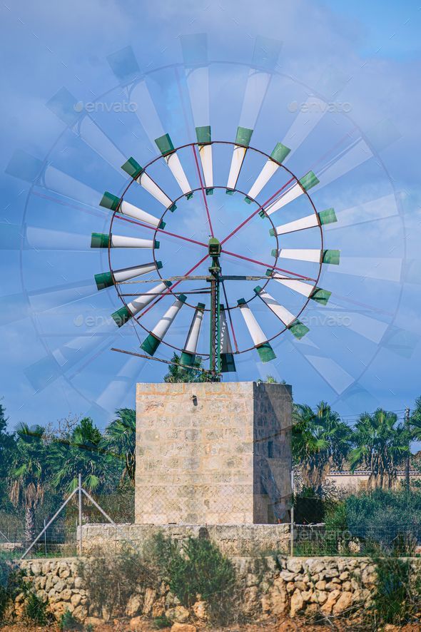 Windmill standing atop a rocky structure against a blue sky. Stock ...