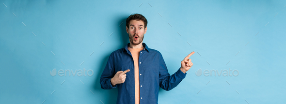 Surprised and amazed caucasian guy gasping in awe, pointing fingers ...