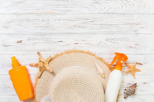 Sunscreen bottles with starfish and sunhat on white wooden table with ...