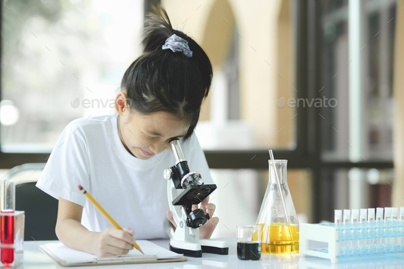 Little child with learning class in school laboratory using microscope ...