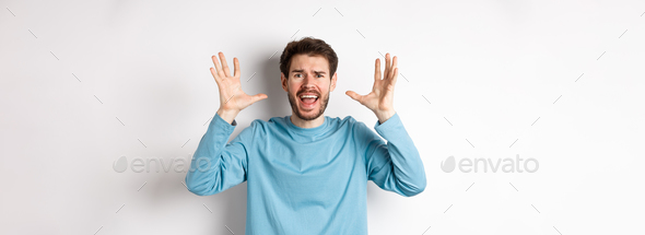 Image of freaked out young man screaming and shaking hands, shouting at ...