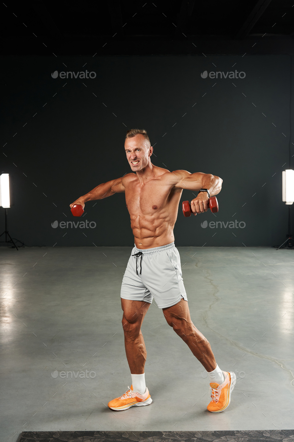 caucasian athlete shakes muscles spreading his arms with dumbbells to ...
