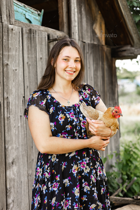 The farmer hugs a hen. pleasant young woman is hugging a cock in ...
