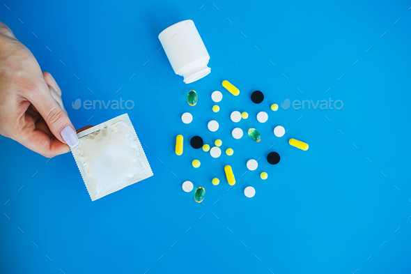Birth Control Pills and an unwrapped Condom. Colored Pills And Capsule ...