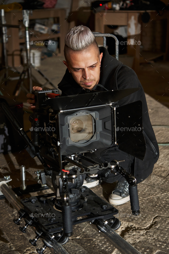 a handsome caucasian cameraman with a haircut sits next to a ...