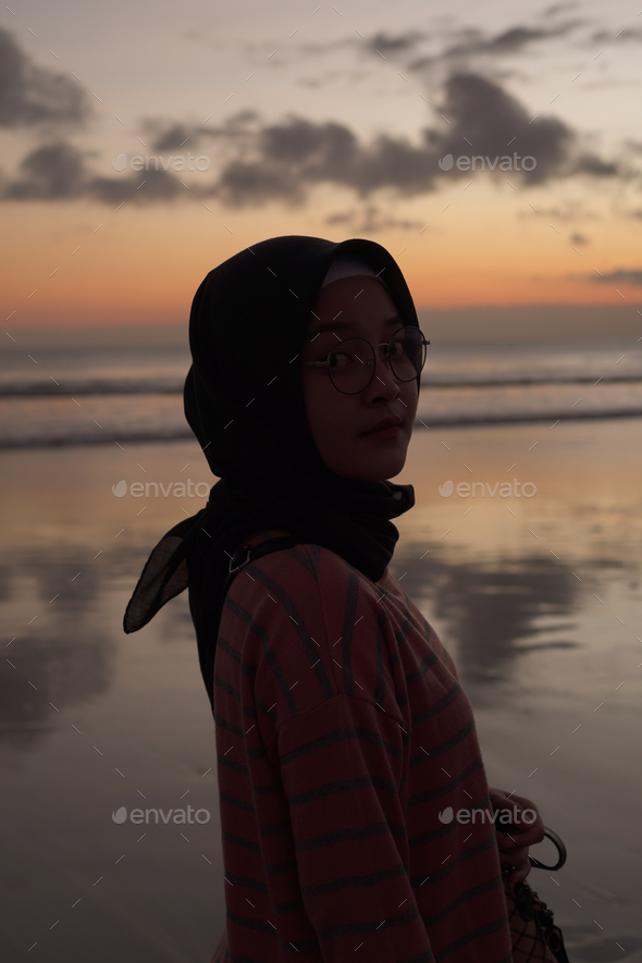 Asian Muslim woman with a hijab standing watching the sunset Stock ...