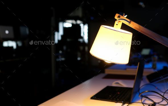 Laptop on the desk in a dark room illuminated by a table lamp Stock ...