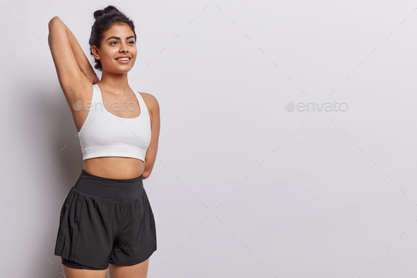 Sporty brunette woman engages in stretching exercises on studio ...