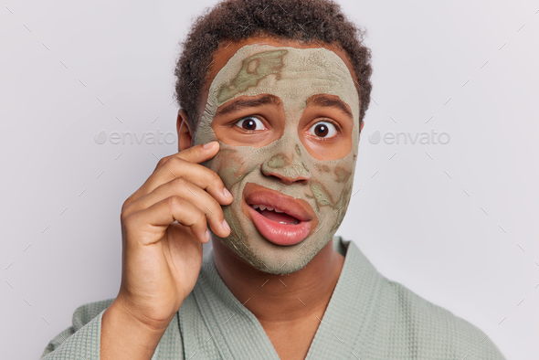 Embarrassed African woman has problematic skin touches face purses lips ...