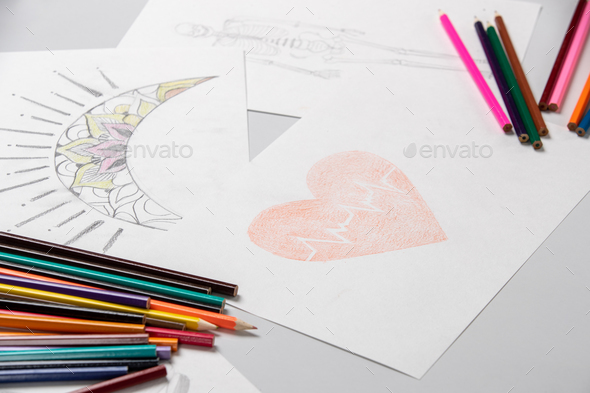 Drawing a painting of a red heart and a moon on the paper laying on the ...