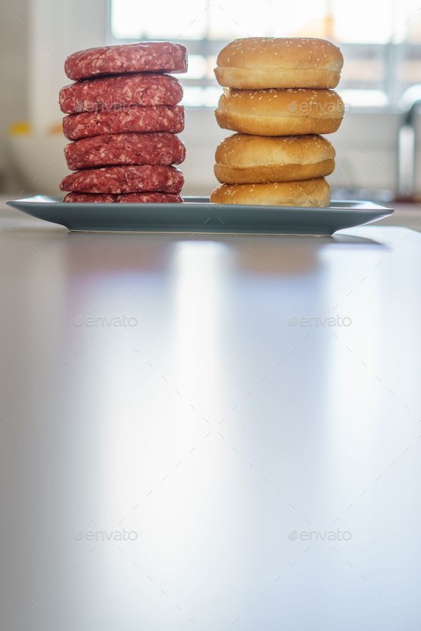 stack of raw beef burgers with their buns Stock Photo by wirestock