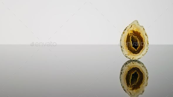 Yellow geode rock crystal with its reflection against a grey background ...