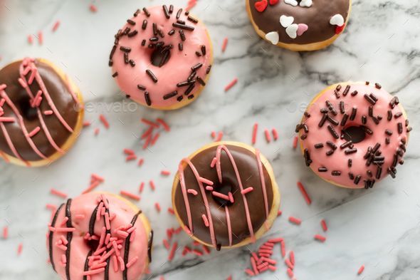 Top view of chocolate and pink donuts messily arranged on a marble ...