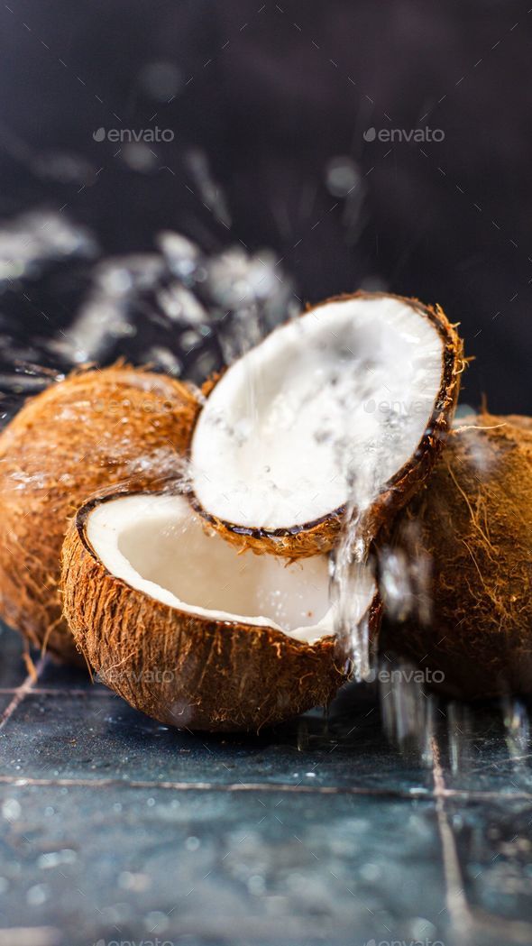 Ripe coconut, split in half, laying on a floor covered in coconut ...