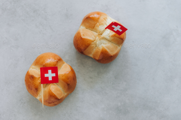 Two buns with cut cross shape and swiss flags.Swiss national holiday on ...