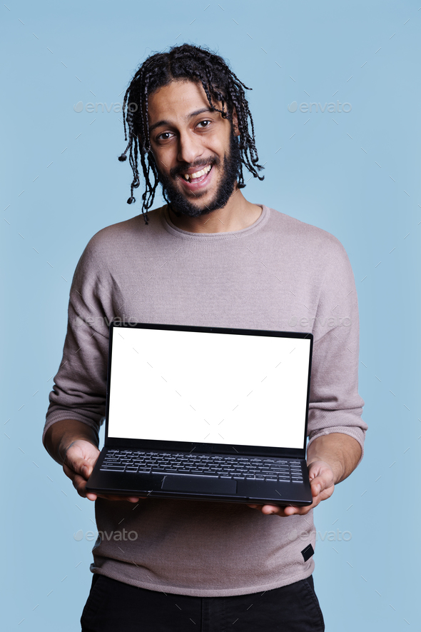 Arab man standing with laptop showing blank screen Stock Photo by DC_Studio