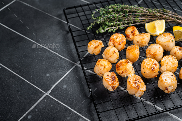 Grilled Scallops fillets on a rack. Black background. Top view. Copy ...