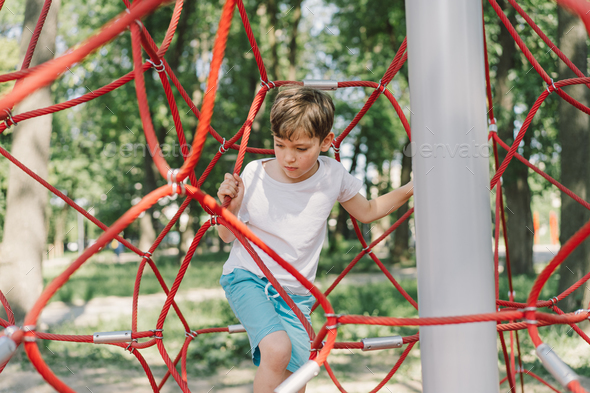 Happy boy child playing in rope spider web at playground Stock Photo by ...